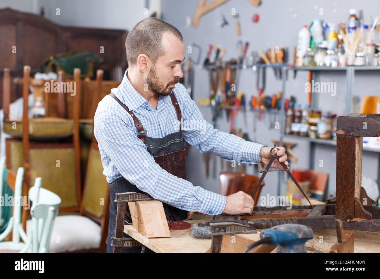 Skilled workman working at repair shop, restoring antique armchair ...