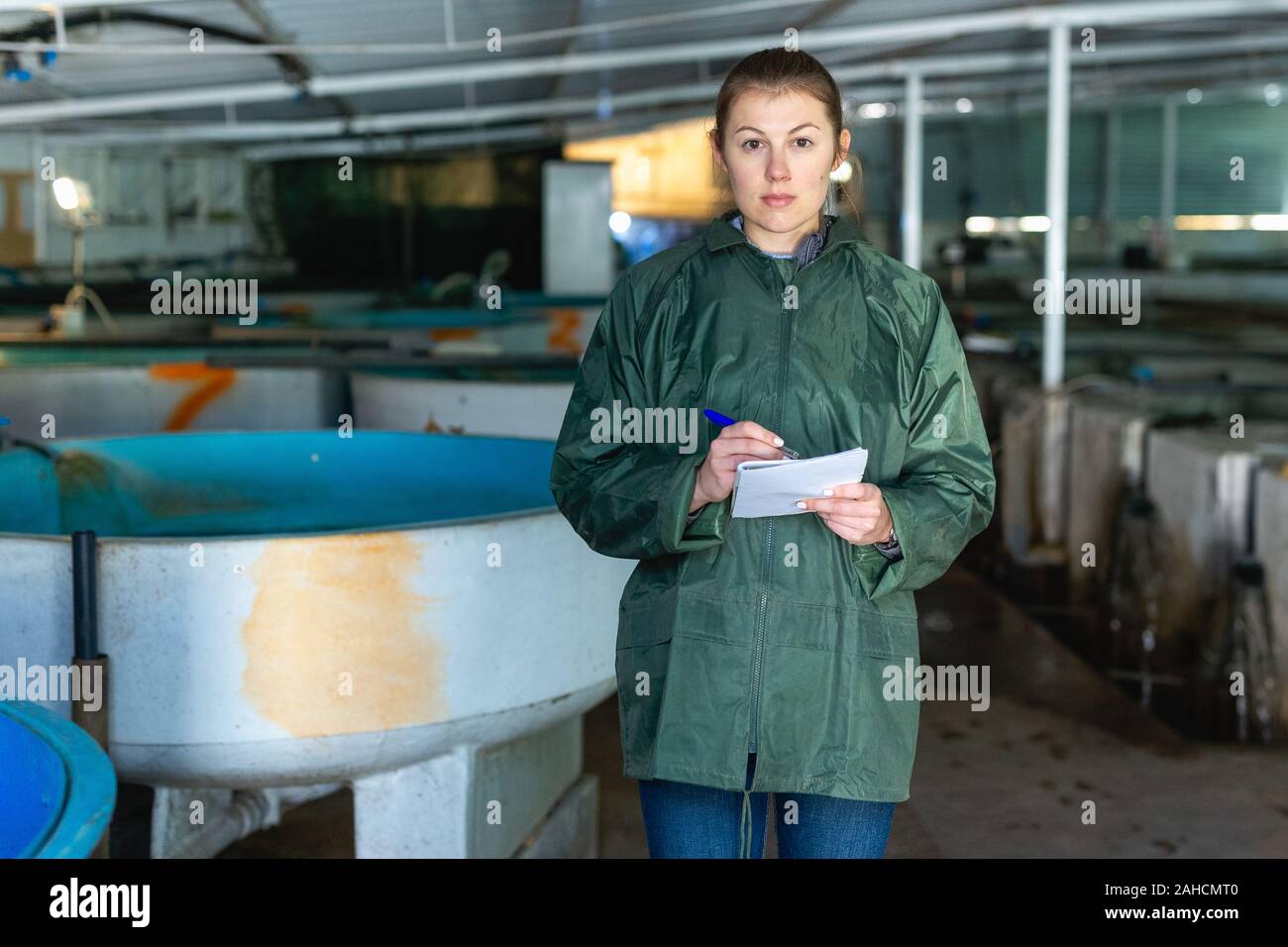 Female fish farm worker checking trout growth in fish breeding ...