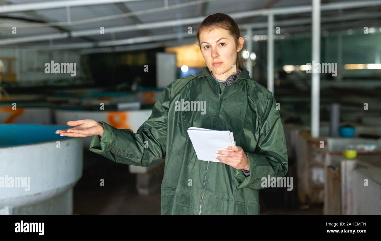 Woman in working clothes controlling fish growth in trout hatchery ...