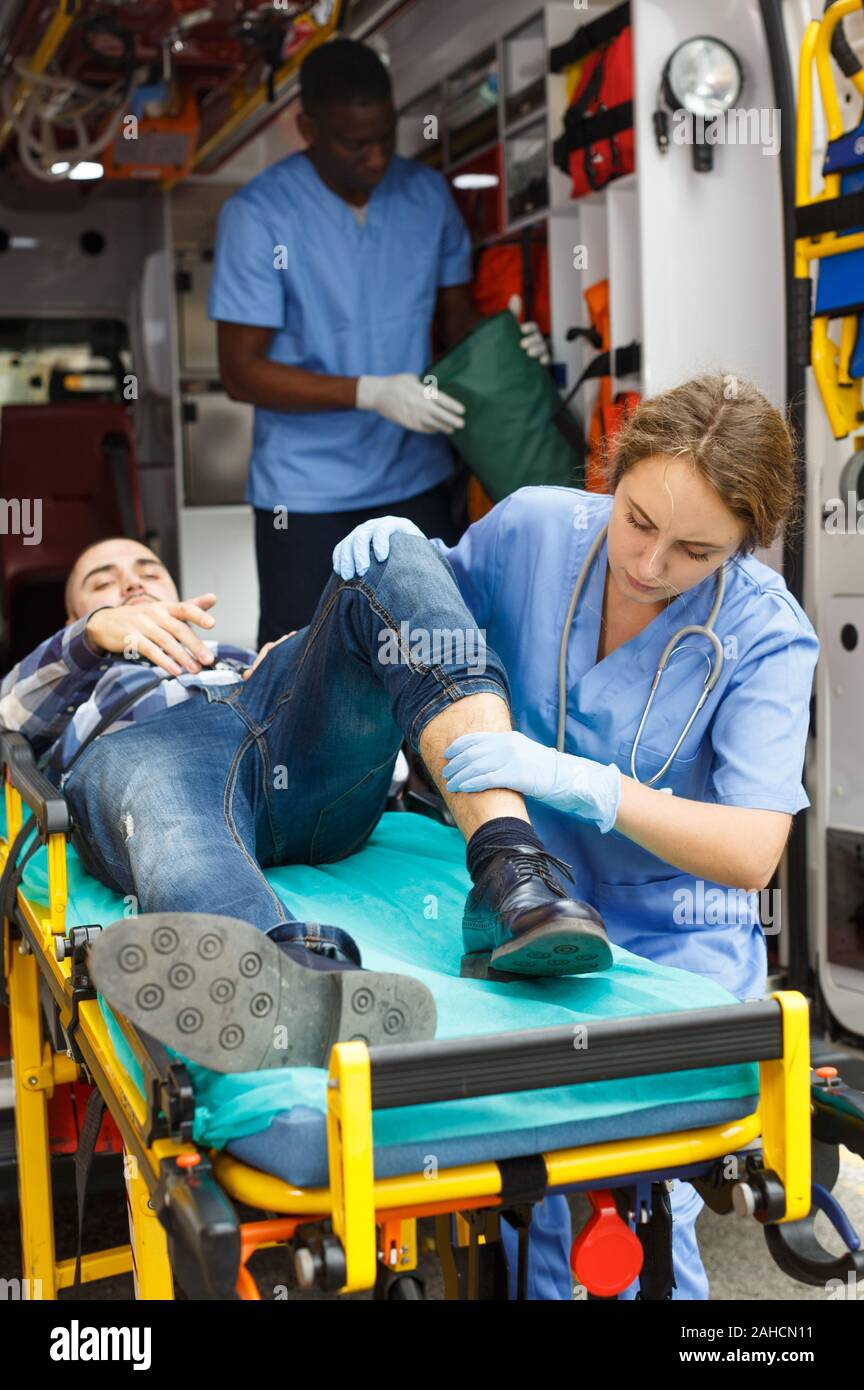 Emergency doctors providing medical care to injured man in ambulance ...