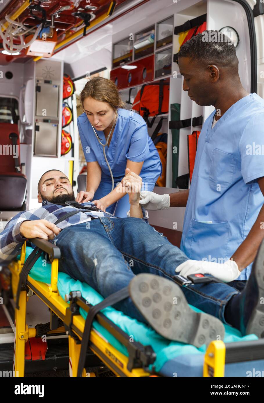 Emergency doctors fixing patient on stretcher in ambulance car Stock ...