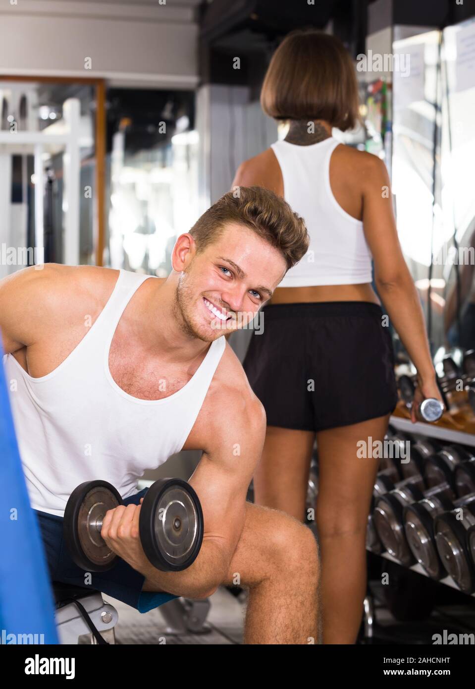 smiling man making biceps curls using heavy dumbbells in gym Stock ...