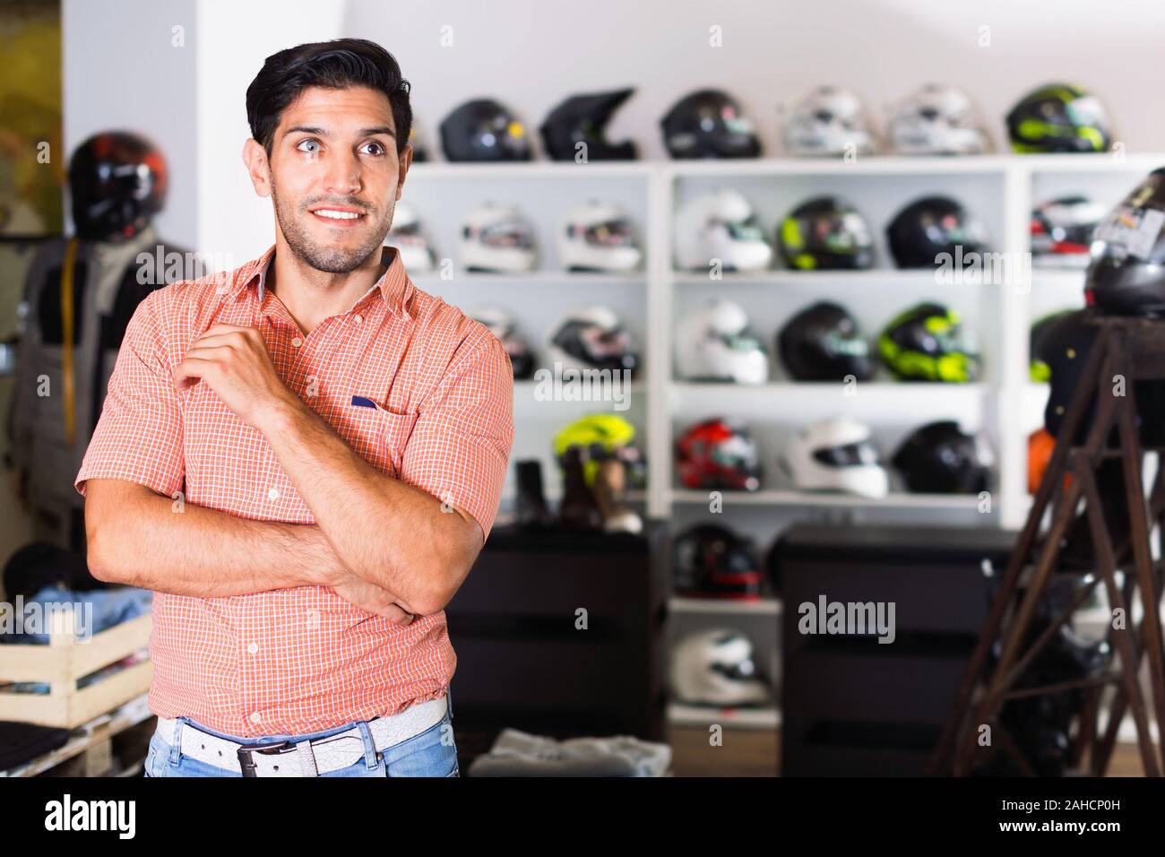 Portrait of glad smiling male customer who is posing in the moto store ...