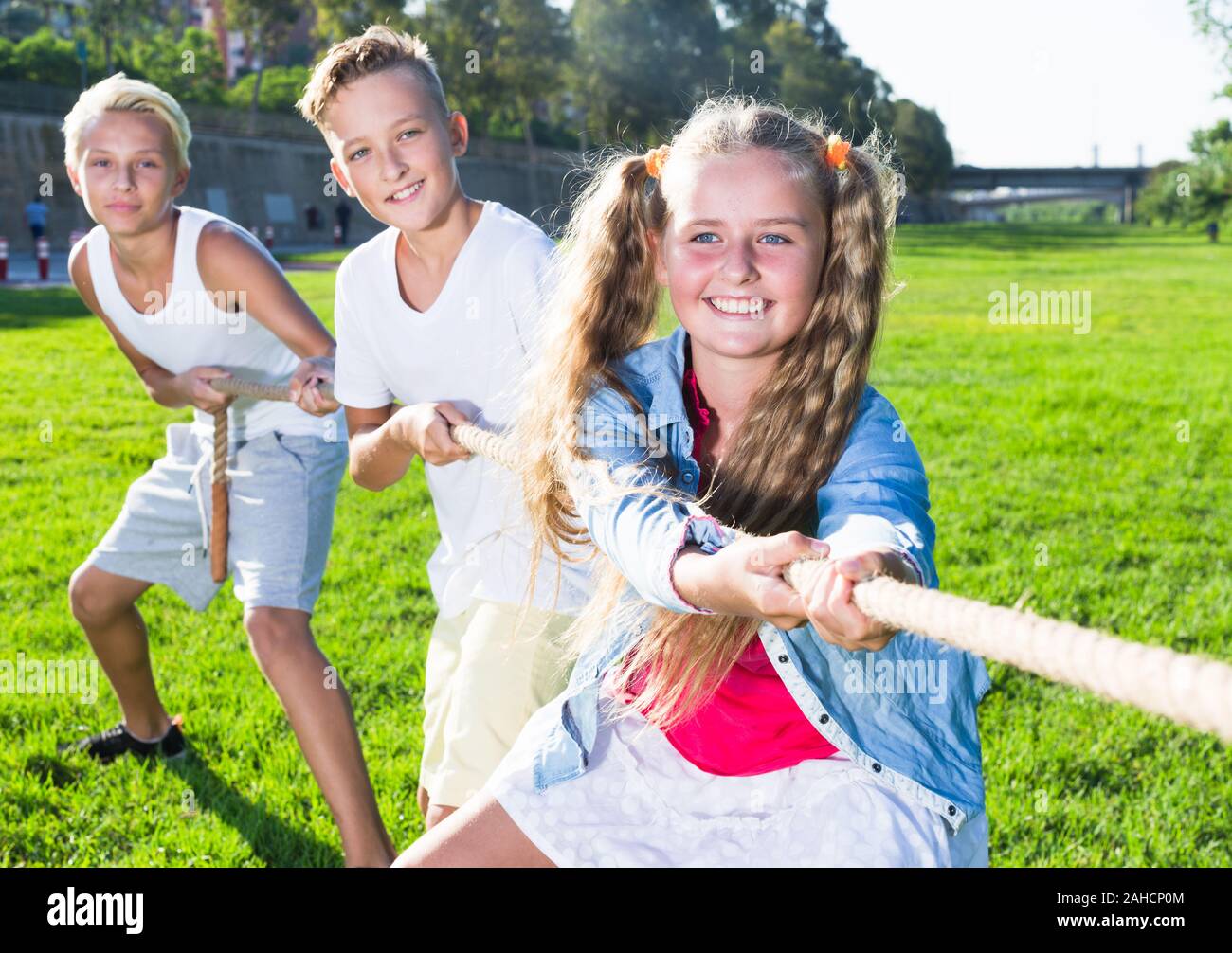 Children playing tug of war during joint games outdoors on sunny day ...