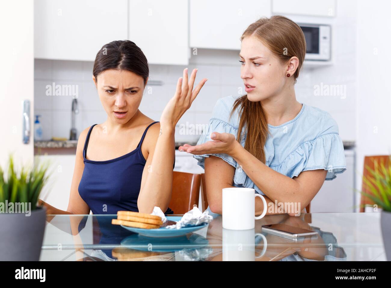 Emotional quarrel between two young women friends in kitchen interior ...