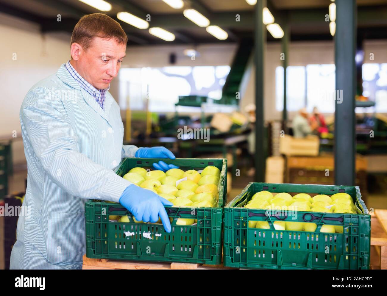 Diligent efficient glad male employee in blue uniform carrying box with ...