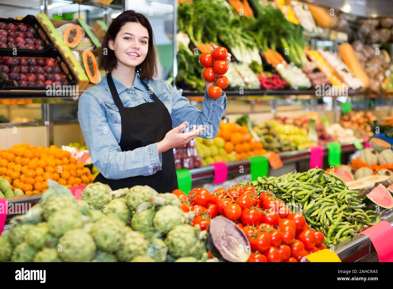 happy female shopping assistant demonstrating assortment of grocery ...
