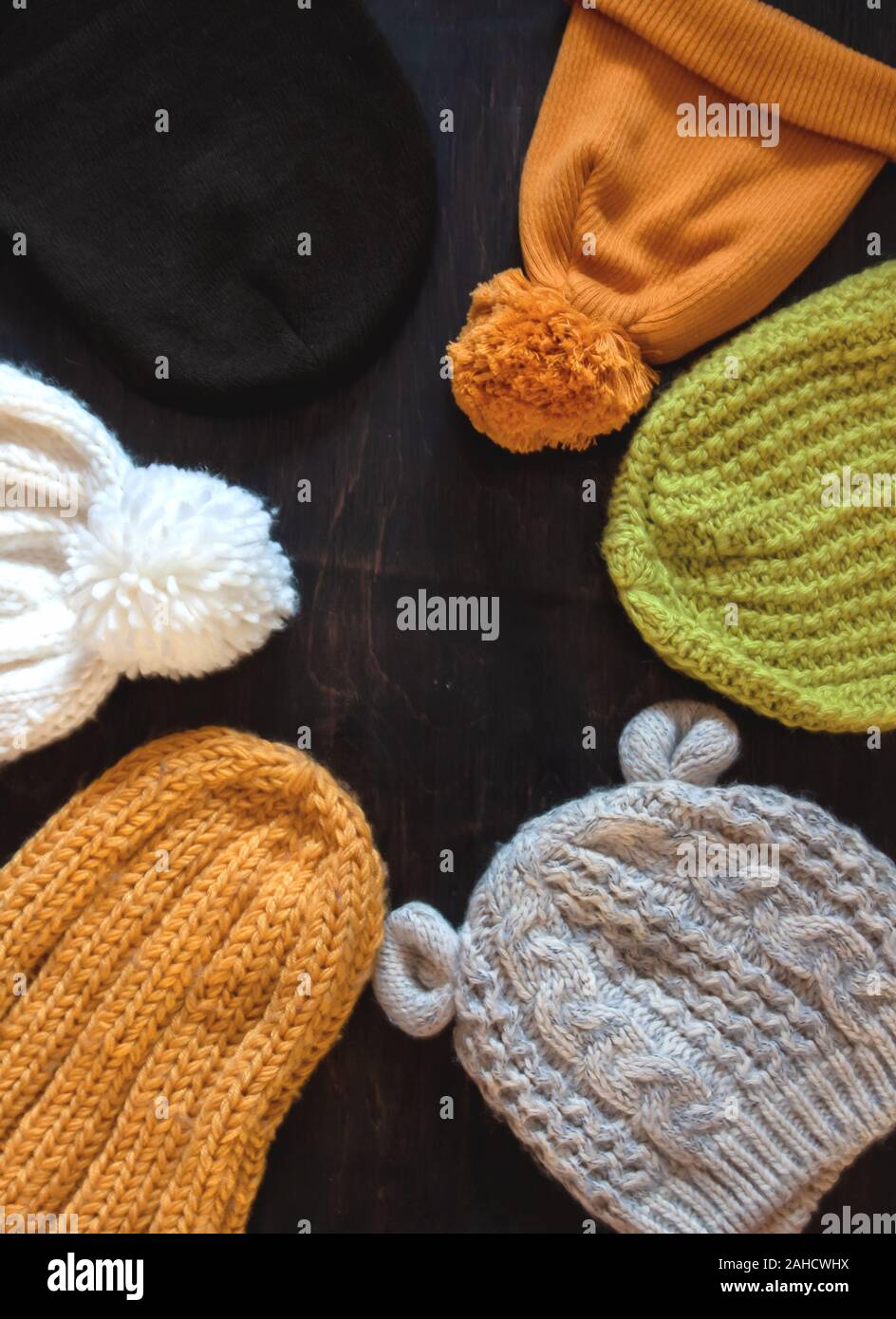 Different types of knitted hats yellow, green, white, gray on a dark ...