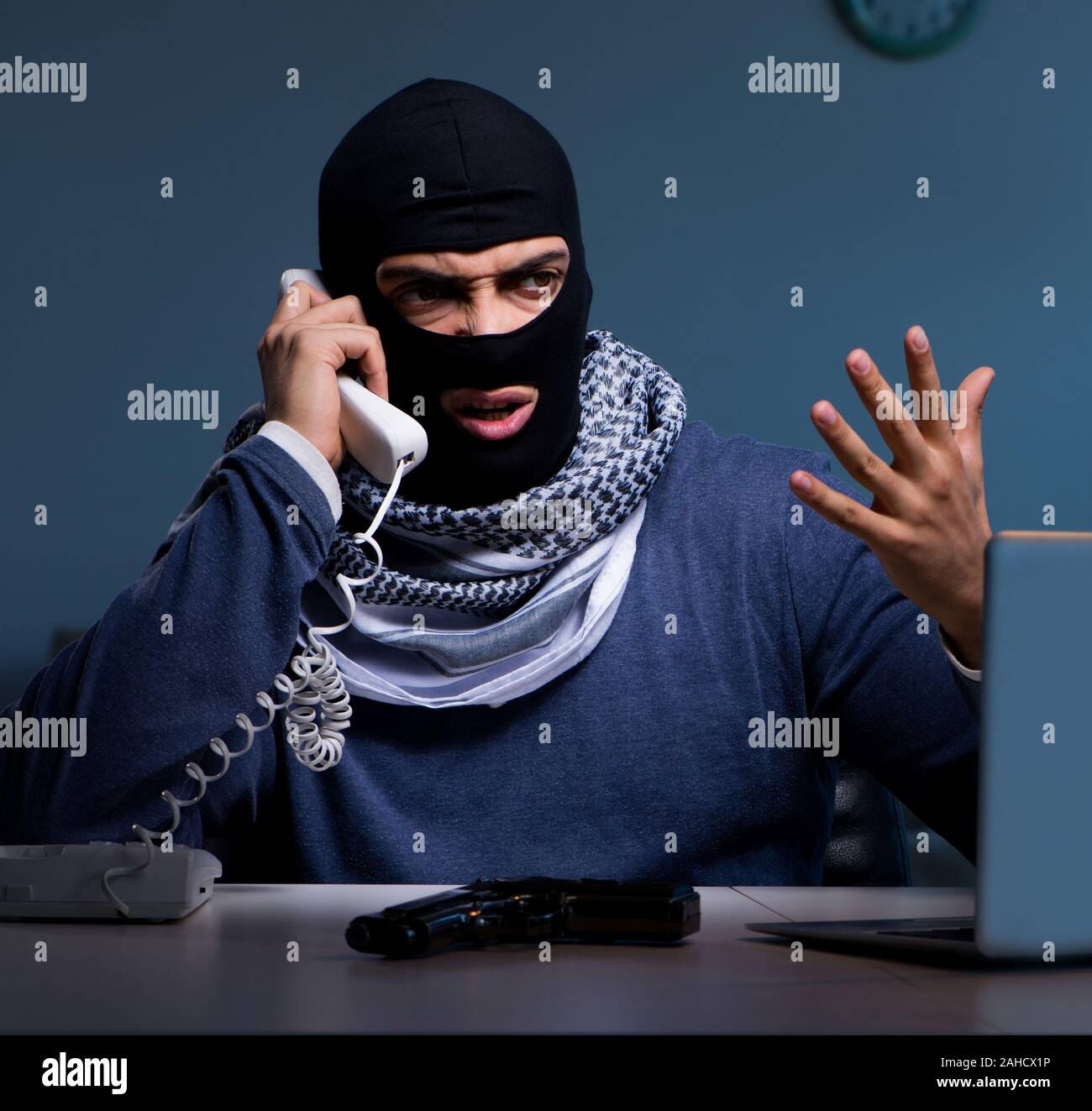 The terrorist burglar with gun working at computer Stock Photo - Alamy