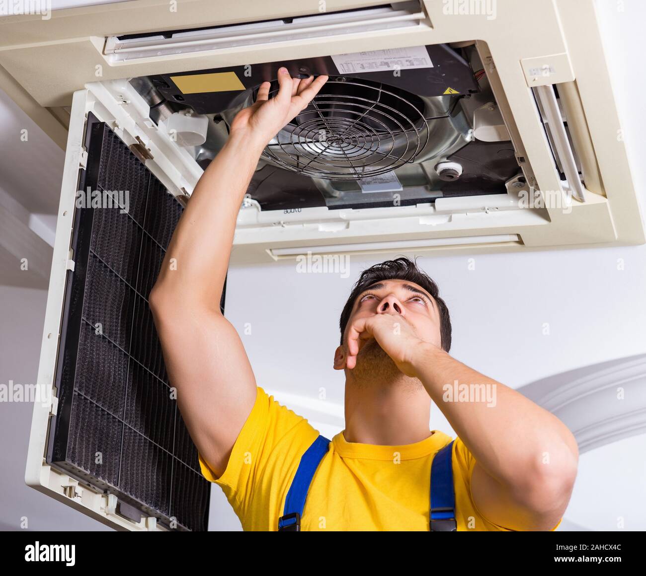 The repairman repairing ceiling air conditioning unit Stock Photo - Alamy