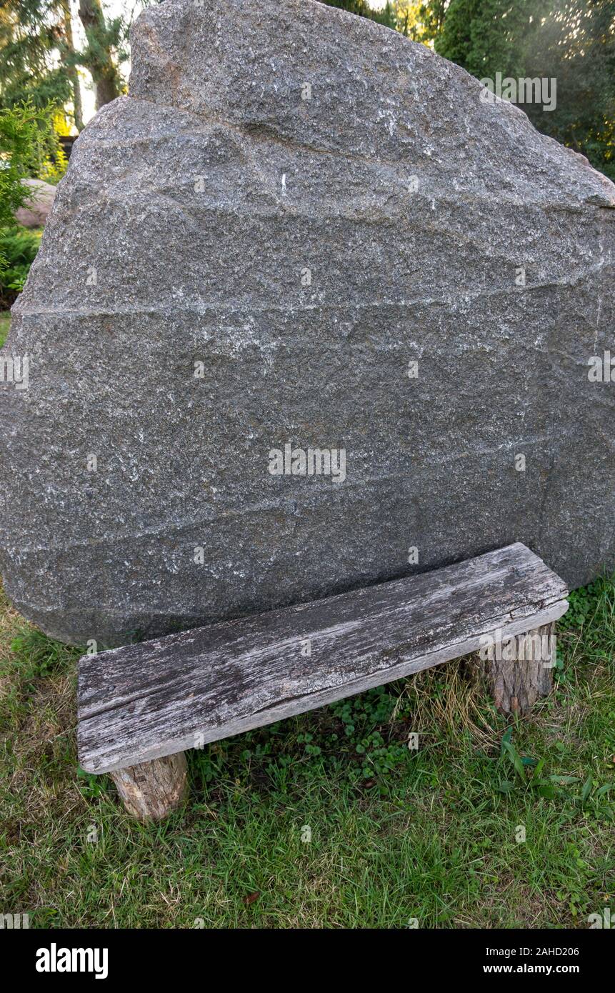 Huge boulder and old bench in the garden Stock Photo - Alamy