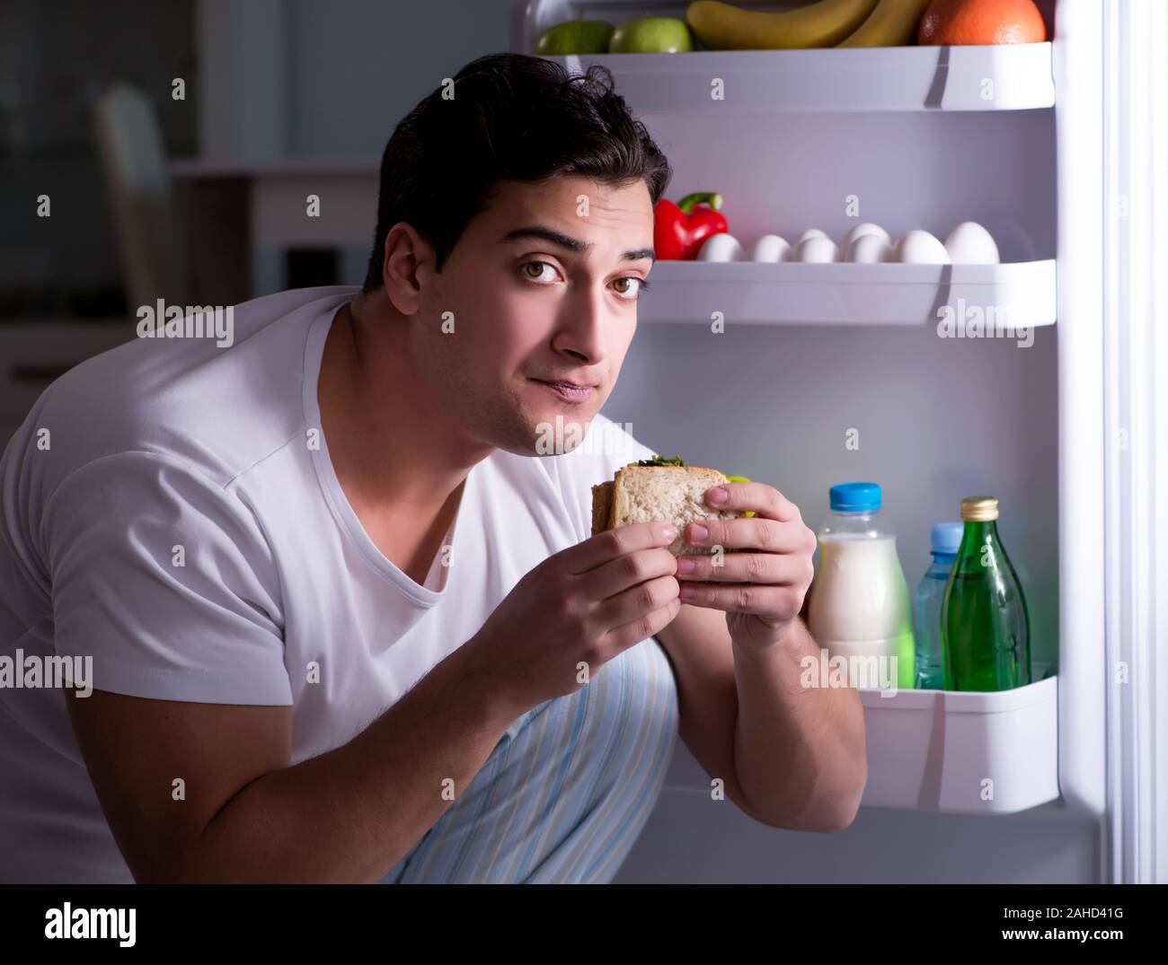 The man at the fridge eating at night Stock Photo - Alamy