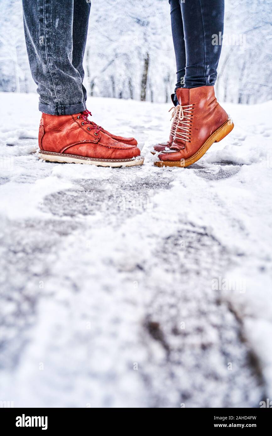 Feet of a couple on a snowy sidewalk in brown boots. Girl stands on ...