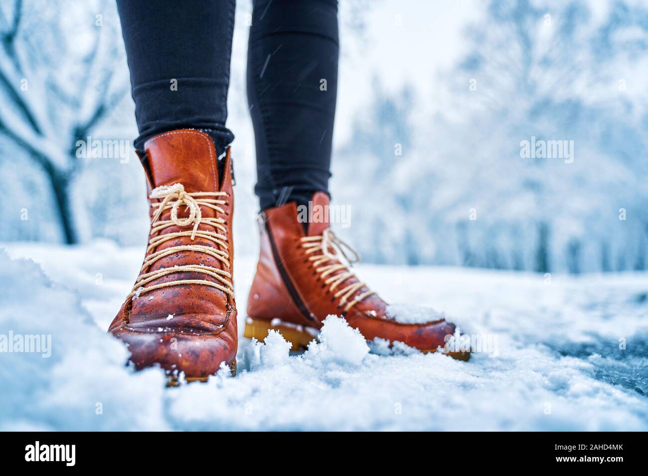 Feet of a woman on a snowy sidewalk in brown boots. Winter slippery ...