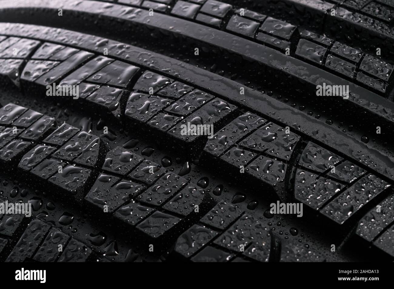 Surface of a new and modern multi season car tyre with water drops ...