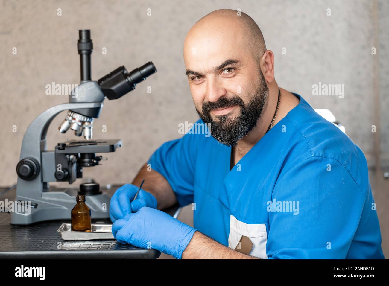 Male laboratory assistant examining biomaterial samples in a microscope ...