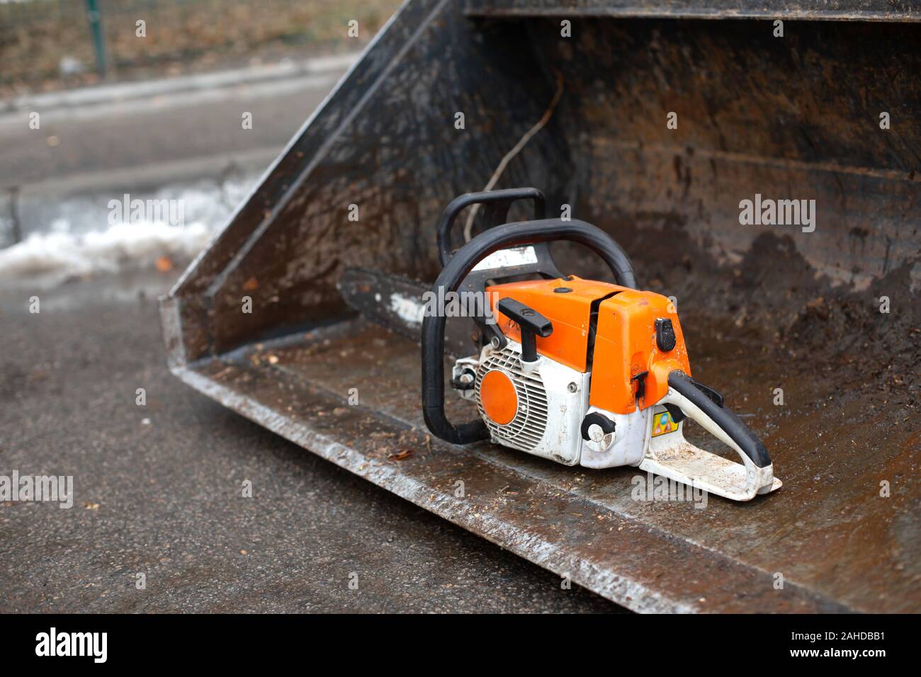 A chainsaw lies in the tractor bucket. Workers cut tree branches Stock ...