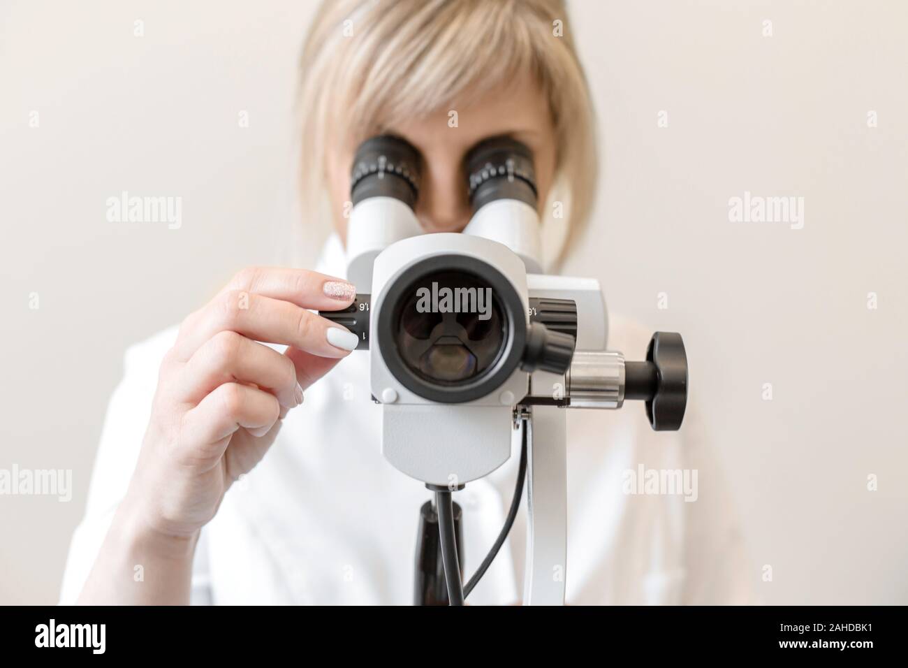 Female blond doctor gynecologist looks through a colposcope ...
