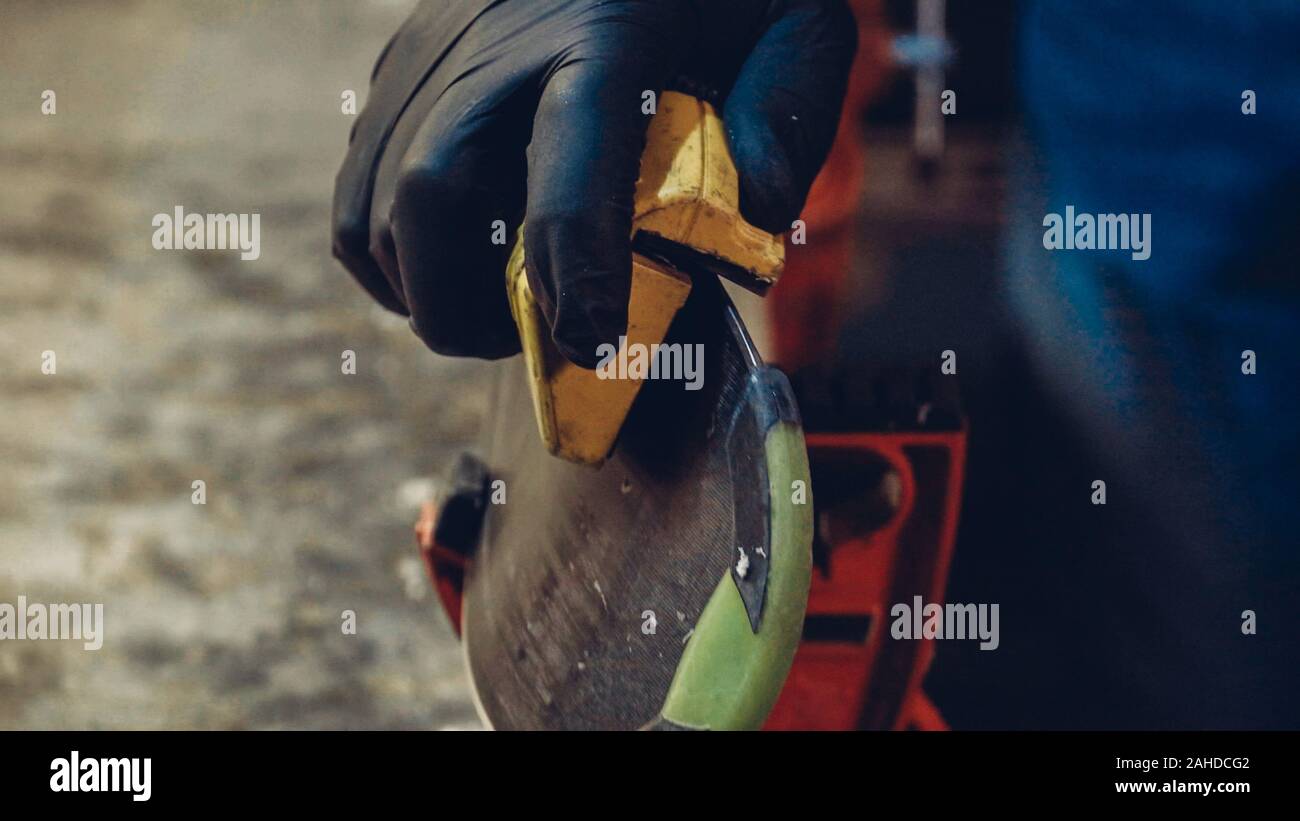 Male worker of ski service workshop doing sharpening and repair of skis ...