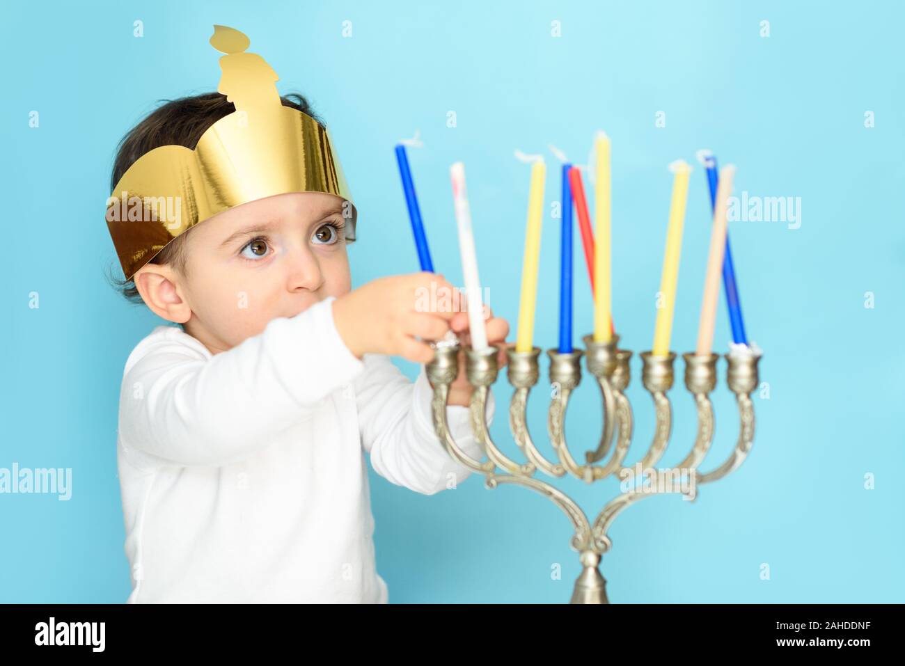 Kid celebrating Hanukkah Israel holiday. Little jewish boy puts candles ...