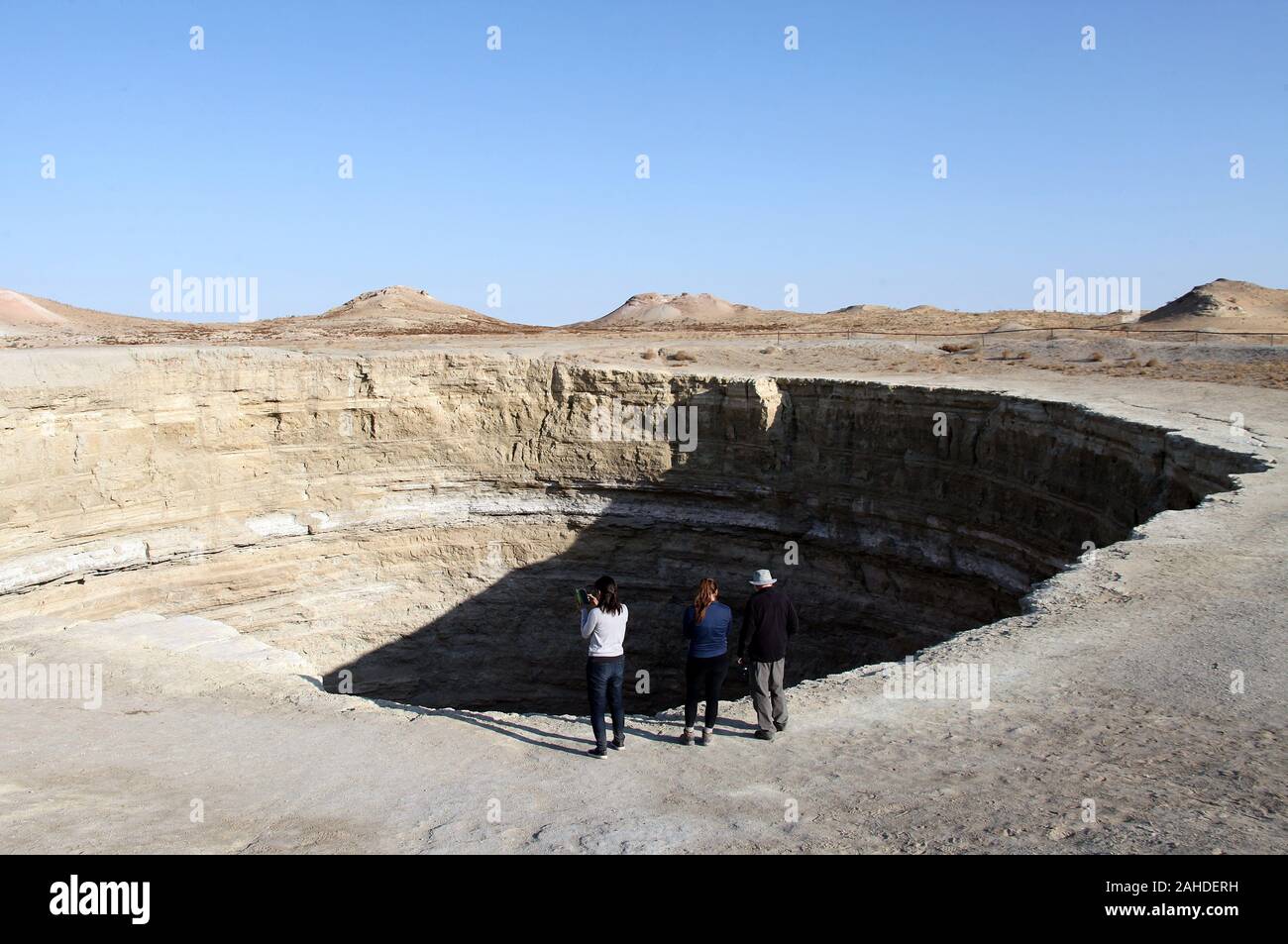 Travellers next to a crater full of bubbling mud at the Karakum desert ...