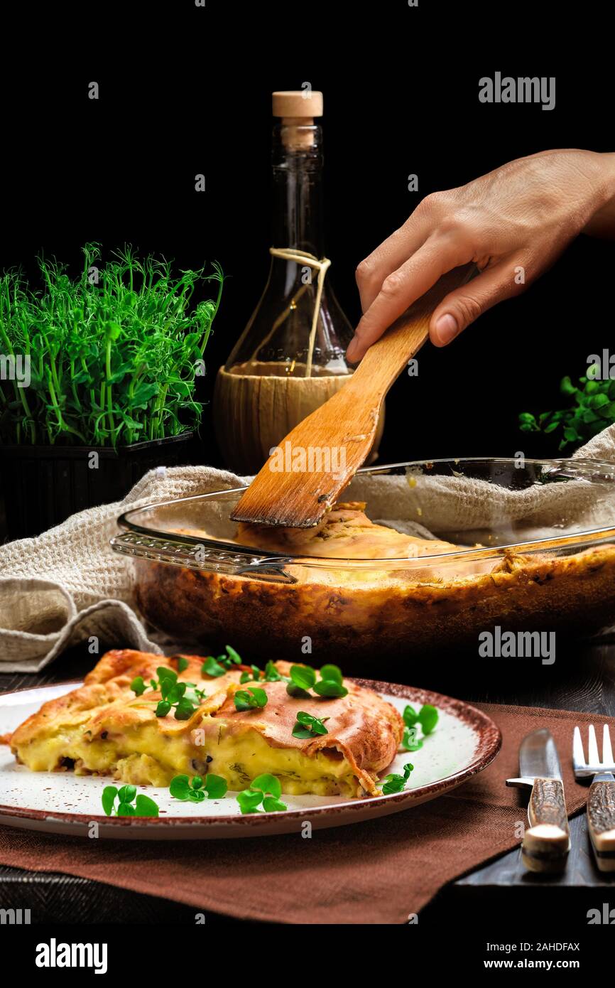 Hand with spatula serving mashed potato casserole baked in oven Stock ...