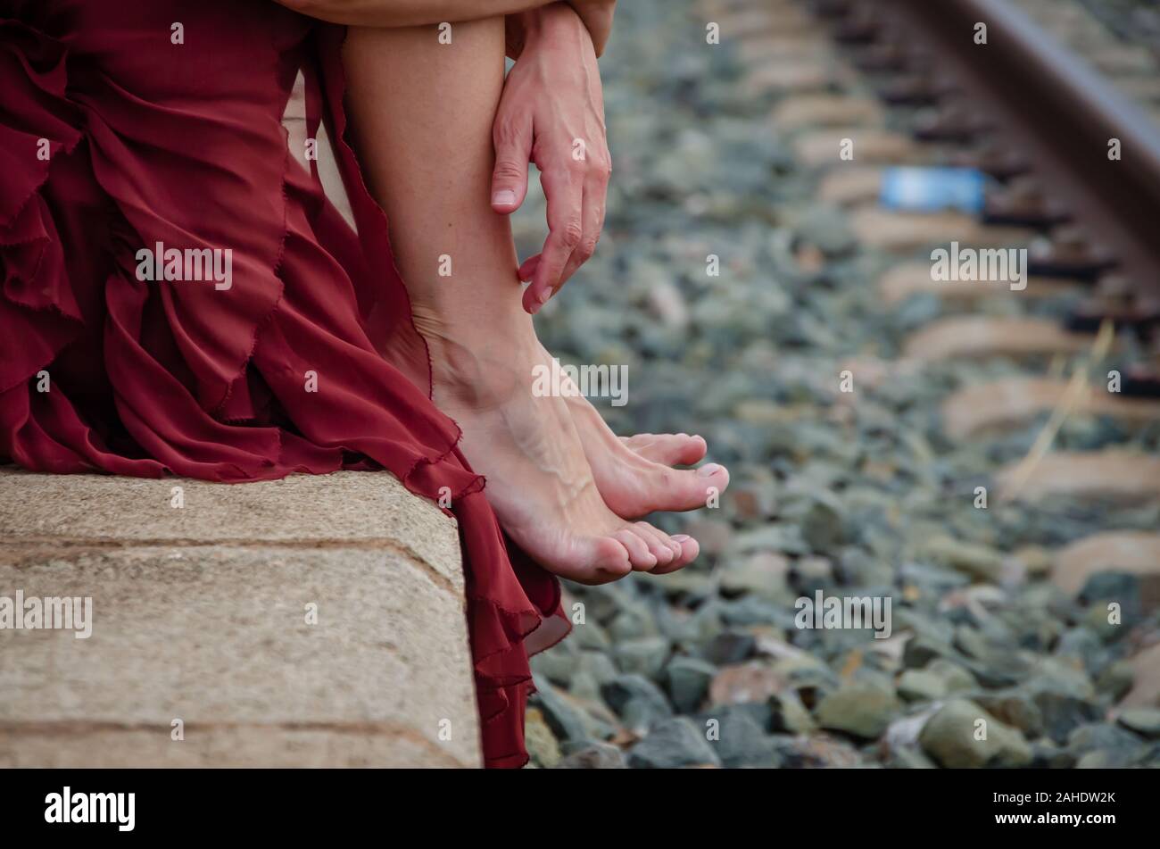 Hands hugging a woman's legs on the train track Stock Photo - Alamy