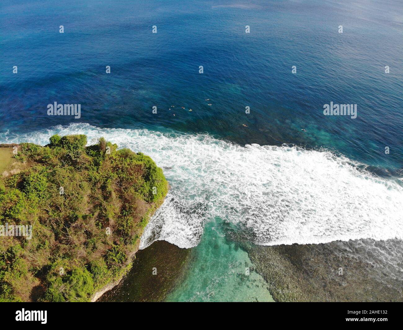 Aerial view of surfer on their board waiting the waves next the cliff ...