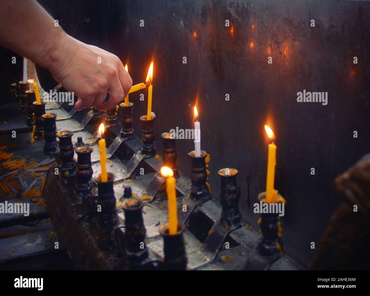 Woman hand lighting a candle as an offering at a buddhist sanctuary ...