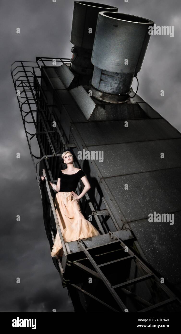 Fashion shoot with a model on ladder and industrial building Stock ...