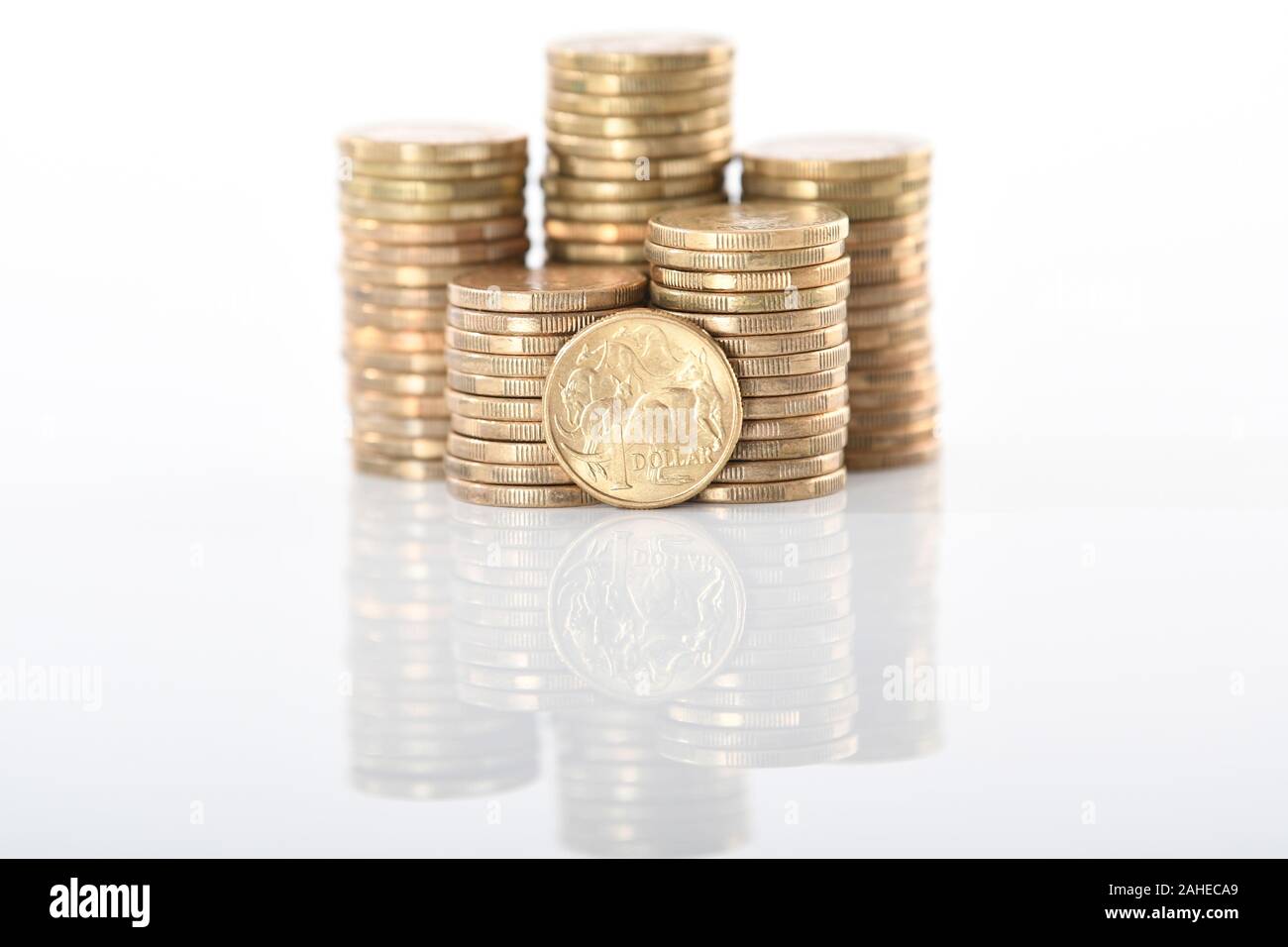A stack of Australian one dollar gold coins set against a white ...