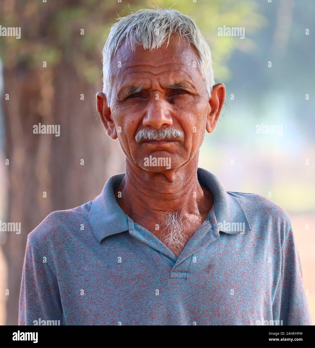 happy old age man(farmer) in blue t-shirt smiling , standing on blurry ...