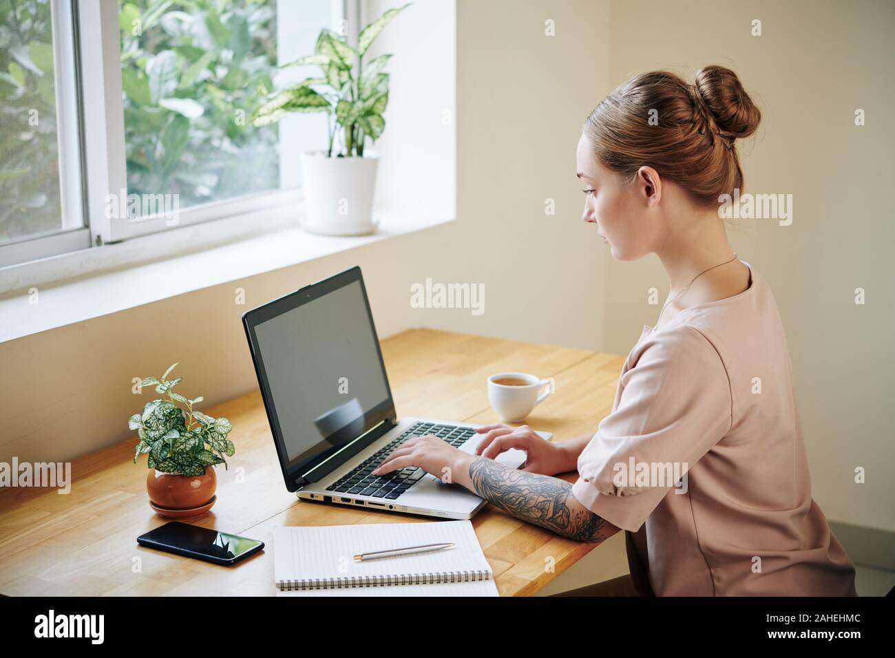 Female student working laptop and writing in textbook when doing ...