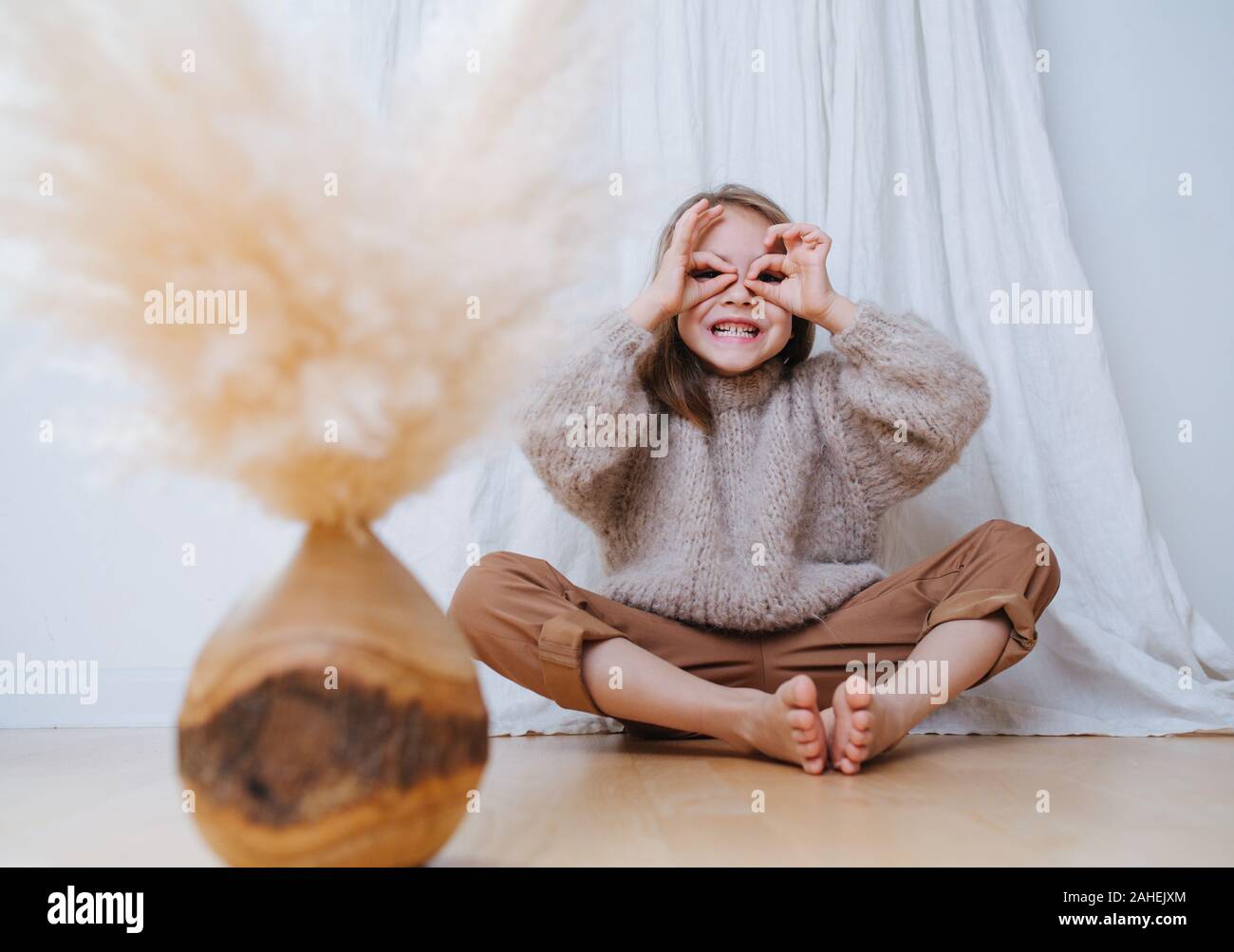 Little girl sitting in butterfly yoga position, grimasing, making ...