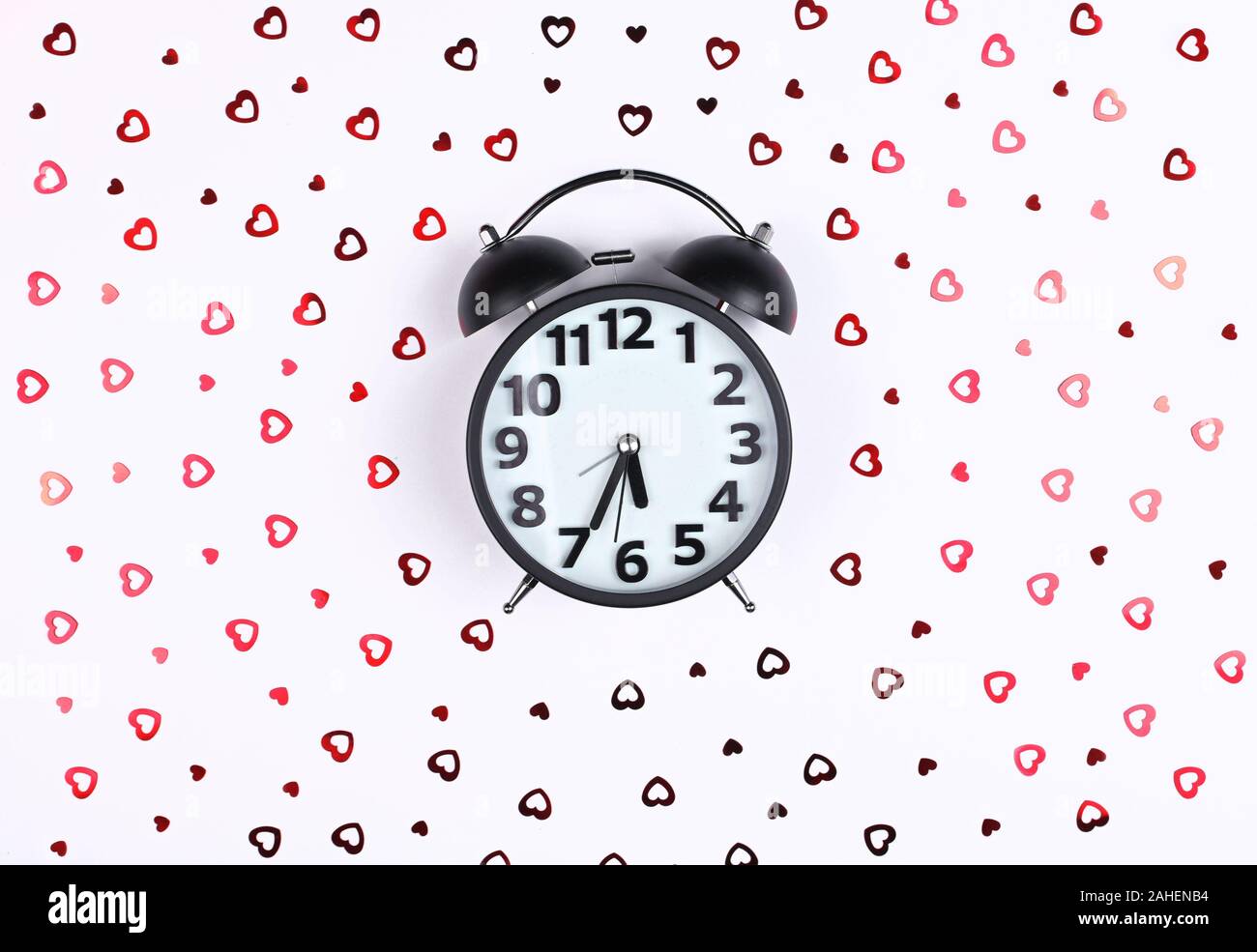 black clock alarm clock on a white background of sequin hearts Stock ...