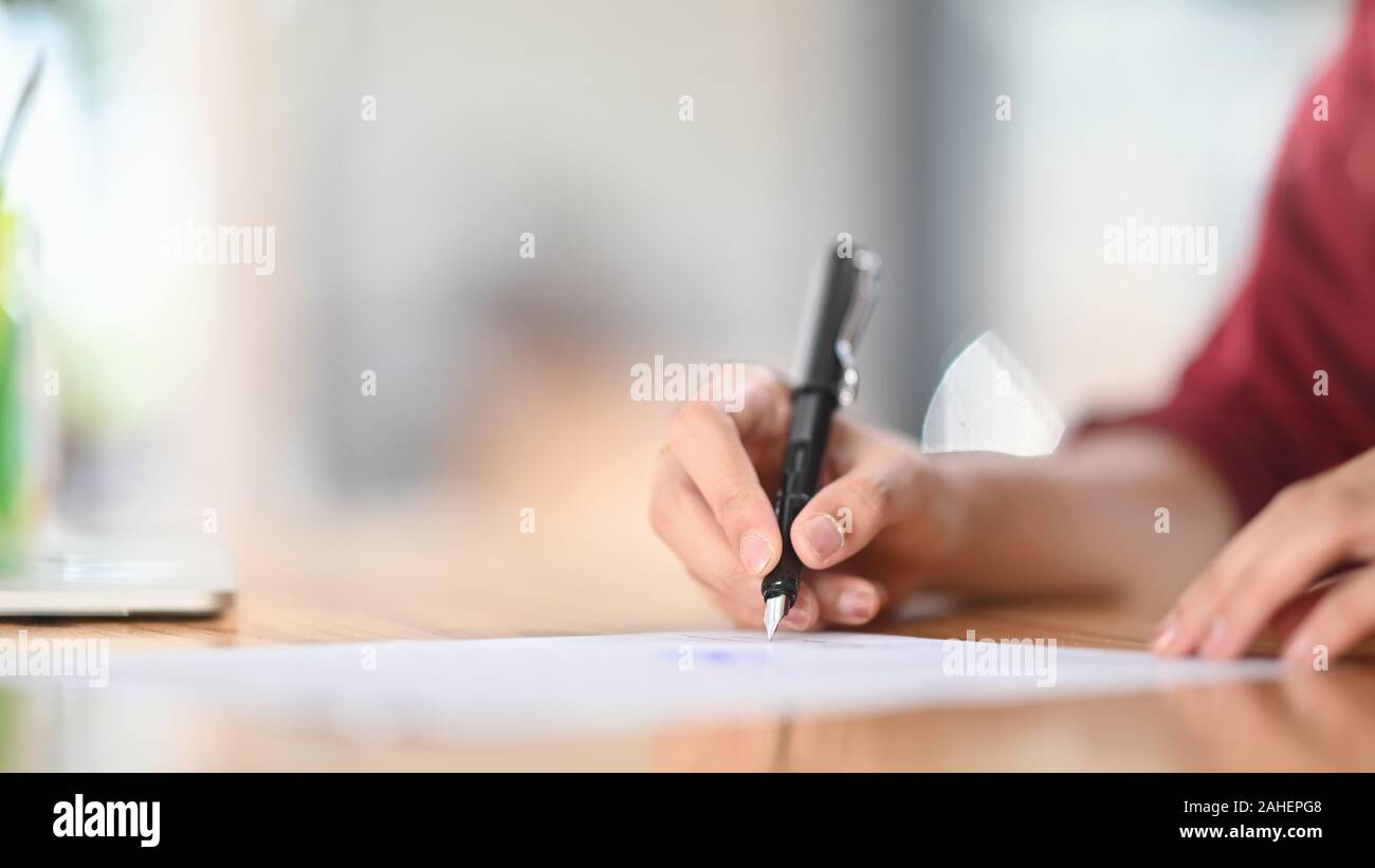 Closeup female signing document focus on her hand holding pen putting ...