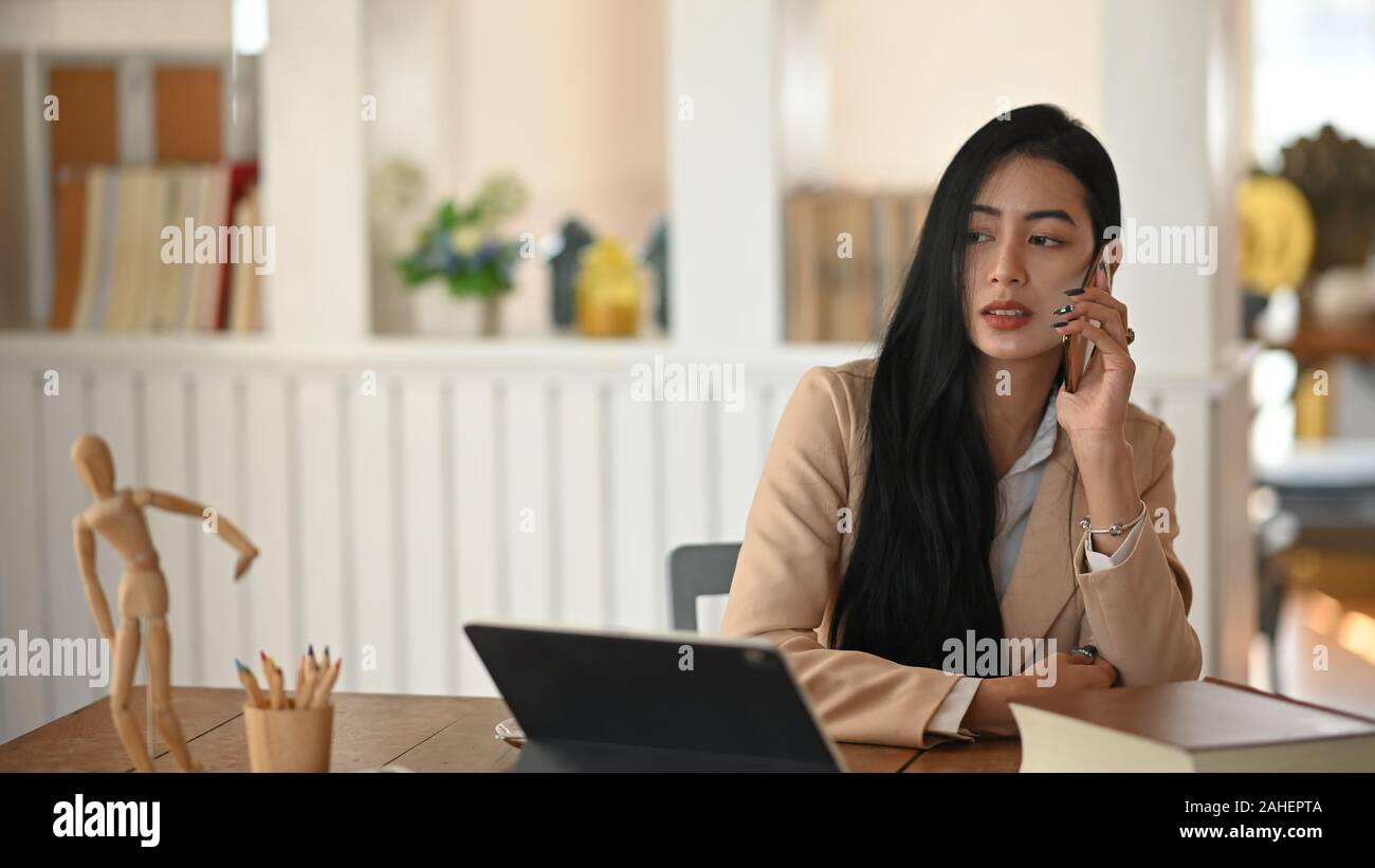 Young woman calling on cell phone in creative work desk Stock Photo - Alamy