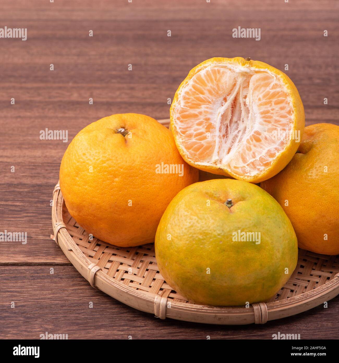 Fresh, beautiful orange color tangerine on bamboo sieve over dark ...
