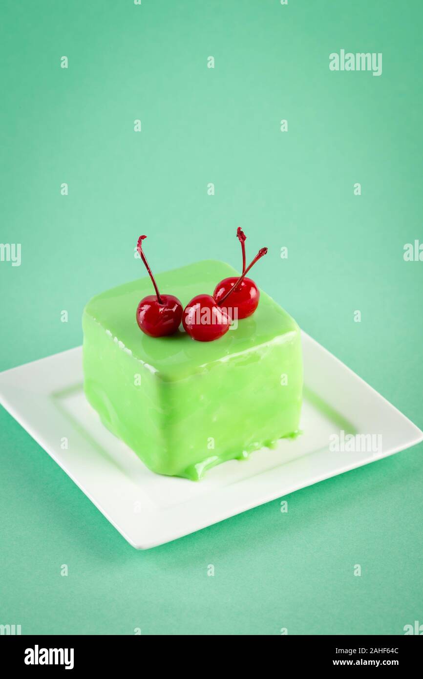Green mousse cake with chery, green background Stock Photo - Alamy