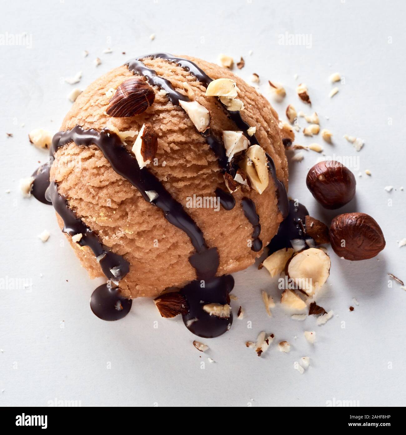 Scoop of hazelnut ice-cream drizzled with chocolate sauce and topped ...