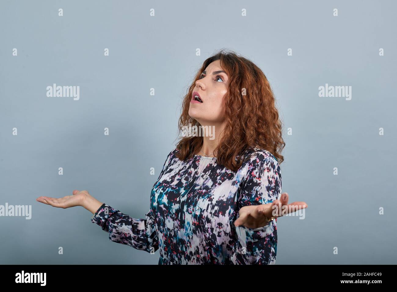 Perplexed caucasian young woman spreads hands, looking up Stock Photo ...
