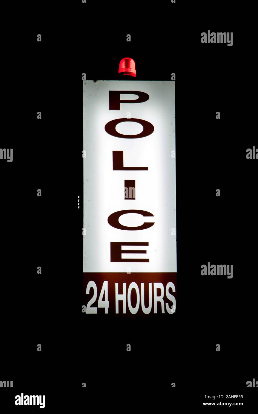 Illuminated police sign with a red flashing beacon at a police station ...