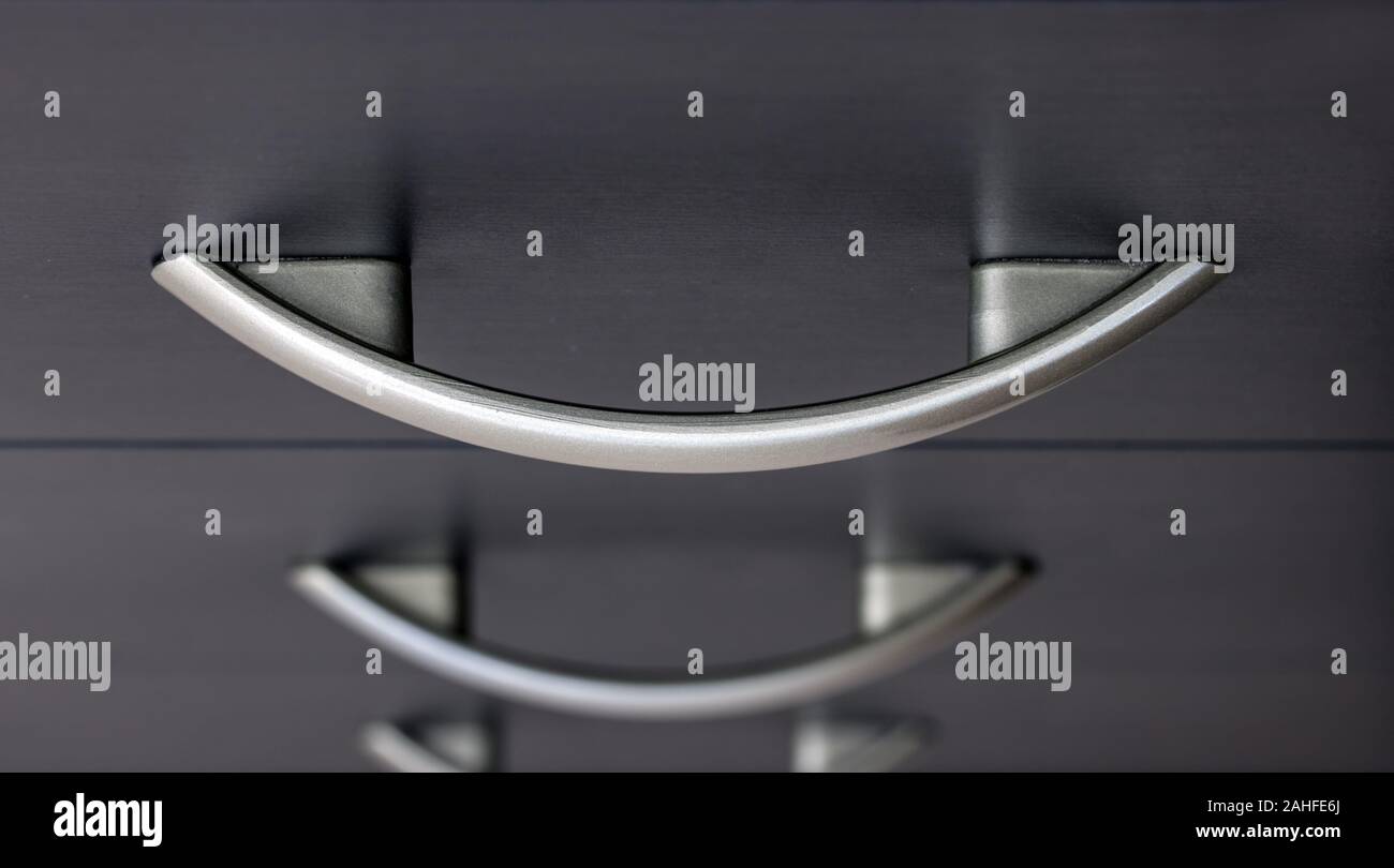 Close-up top view of drawers. Row of black drawers with arched handles ...