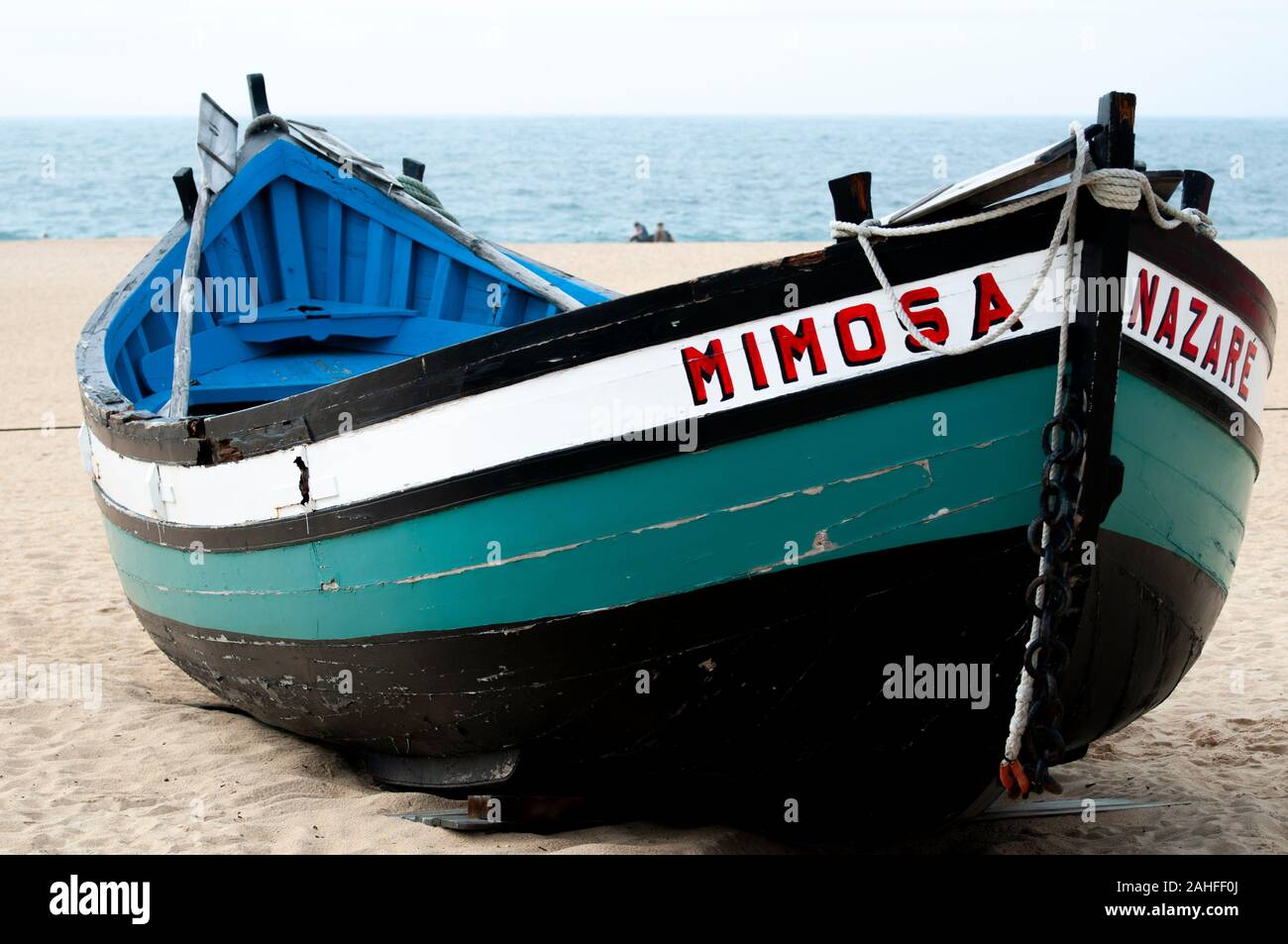 Traditional green and black wooden Portuguese fishing boat on the beach ...