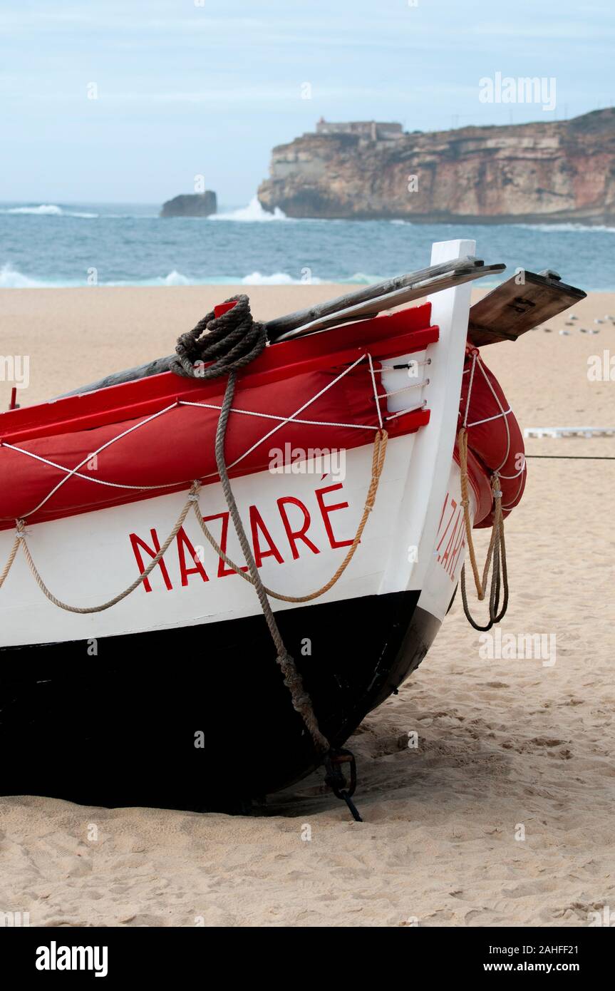 Traditional red and white wooden Portuguese fishing boat on the beach ...