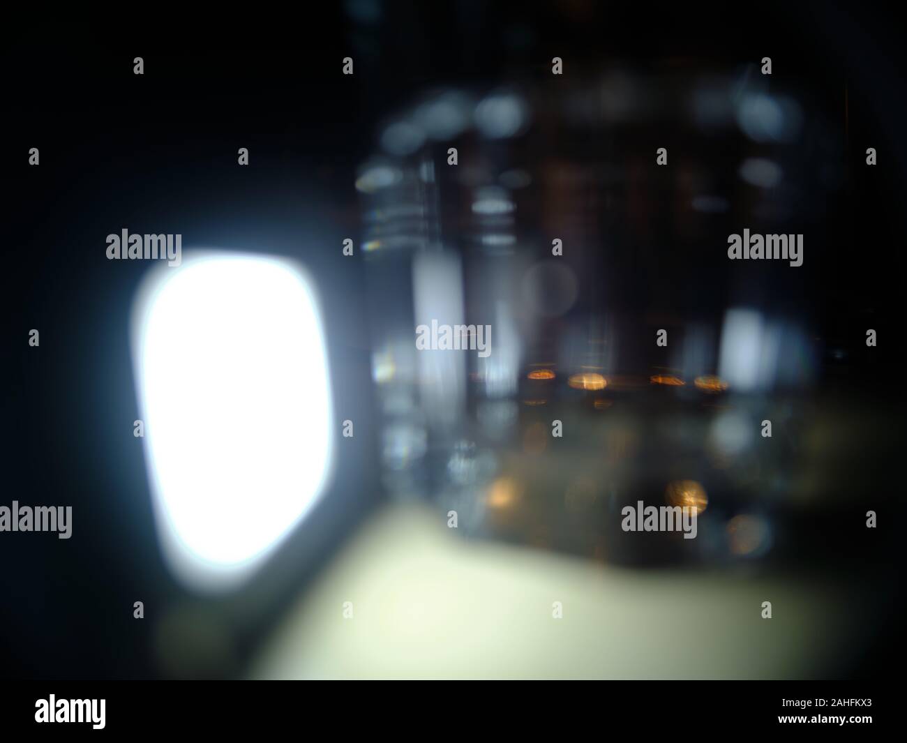 Blurry light effects, of out of focus glasses, in front of a dark ...