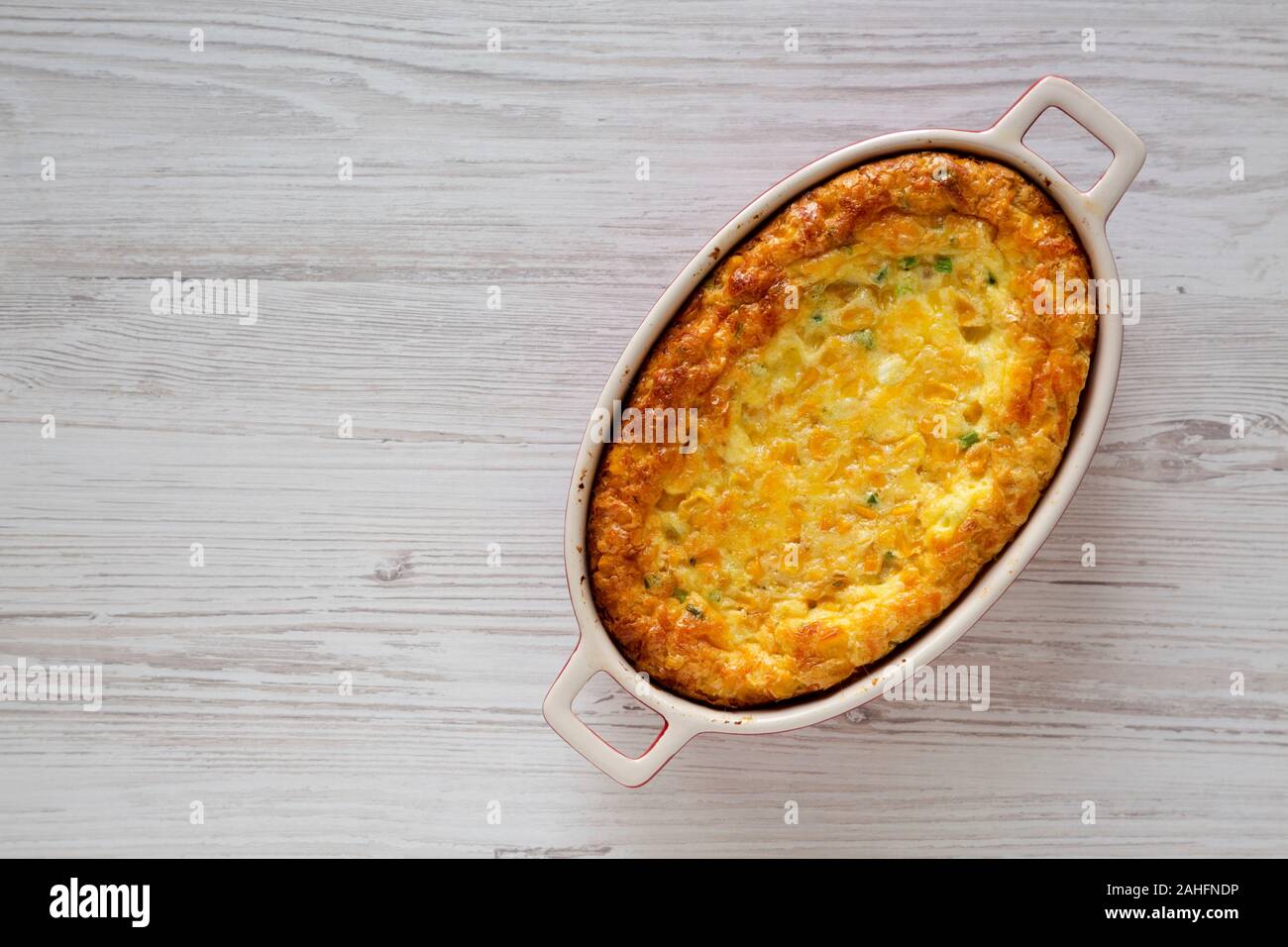 Homemade Cheddar Corn Pudding Casserole on a white wooden background ...