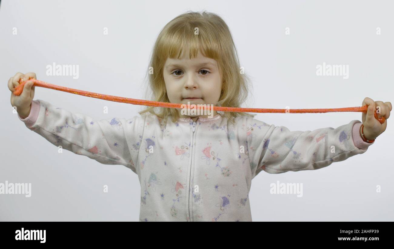 Child having fun making orange slime. Kid playing with hand made toy ...