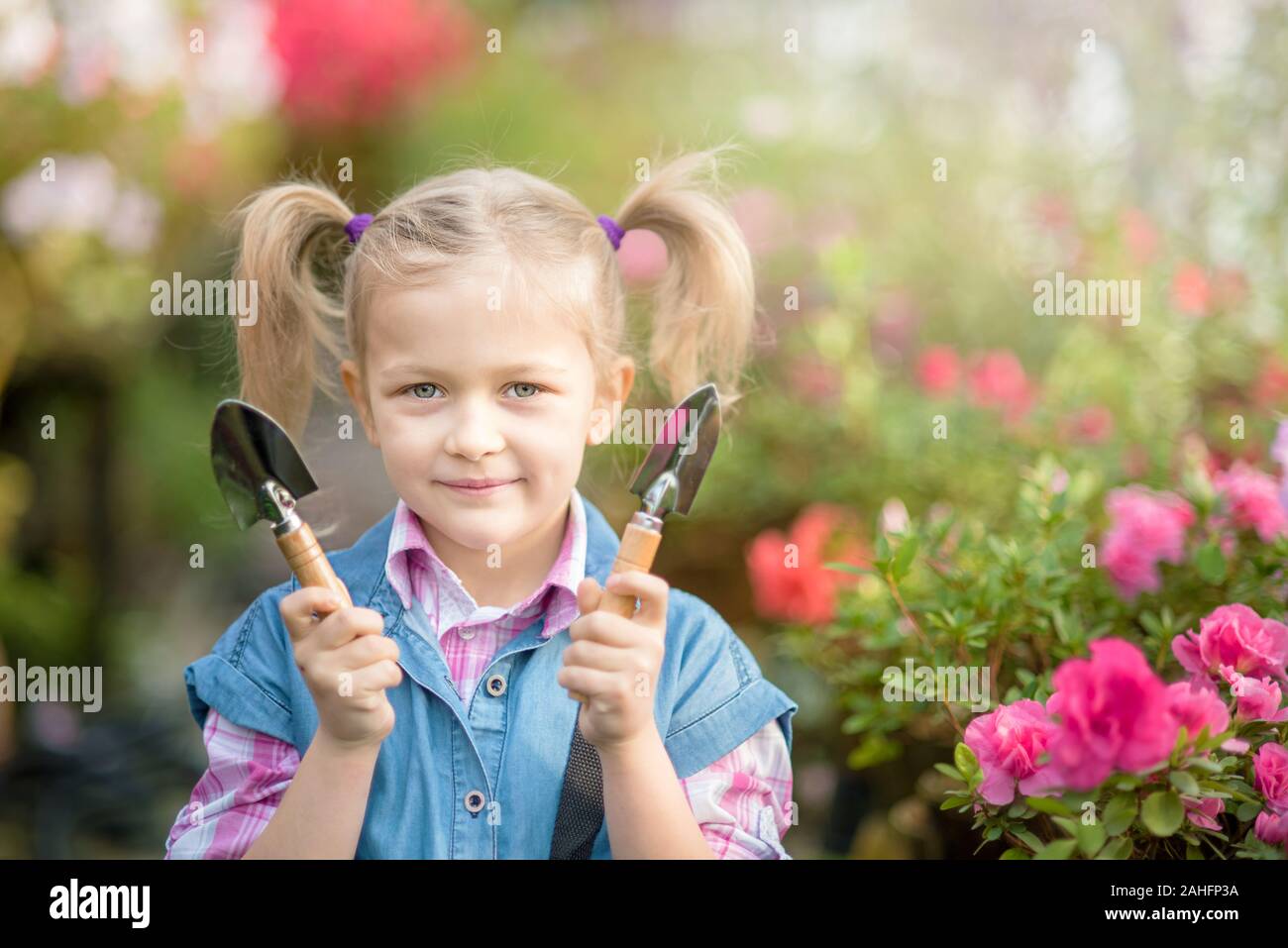 Child planting spring flowers in greenhouse. Little girl gardener ...