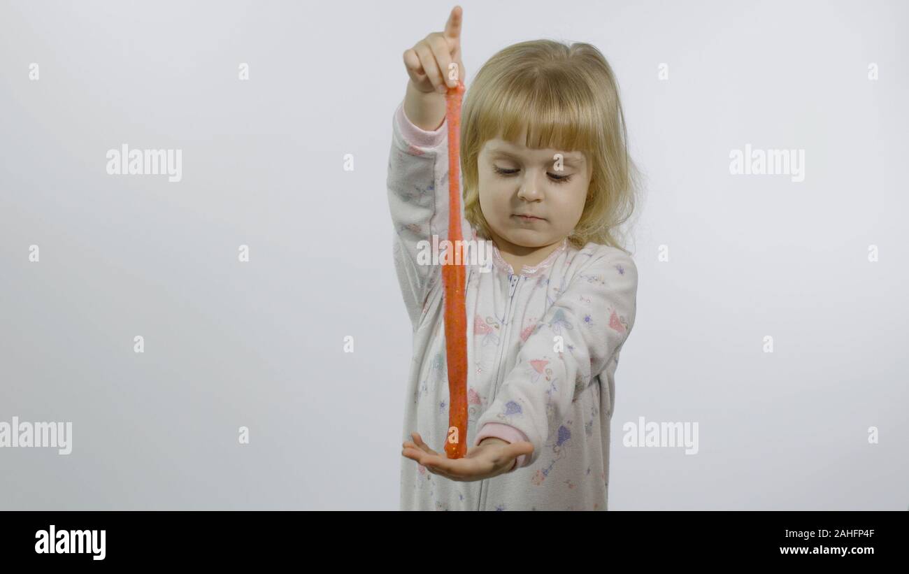 Child having fun making orange slime. Kid playing with hand made toy ...